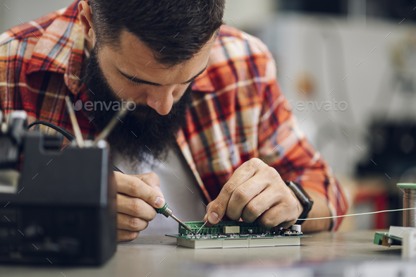 Electronics engineer working in a workshop with tin soldering parts ...