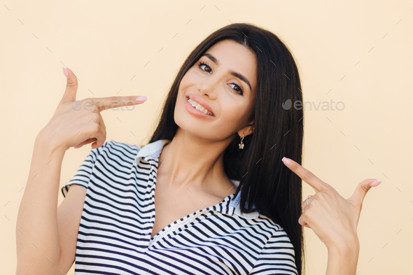 Horizontal portrait of happy brunette female model has broad smile ...