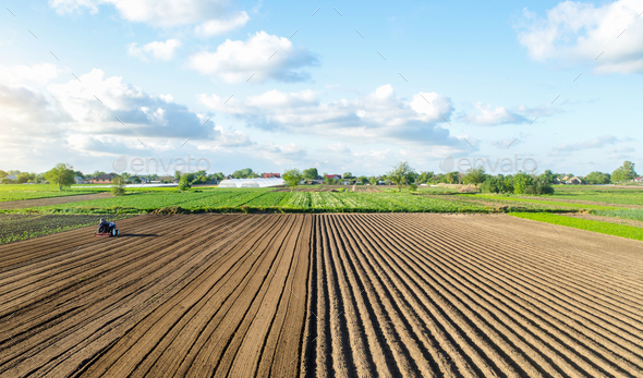 Farm field landscape and a tractor. Agricultural industry. Stock Photo ...
