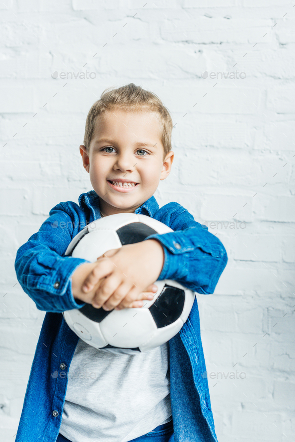 happy little kid with football ball looking at camera in front of white ...