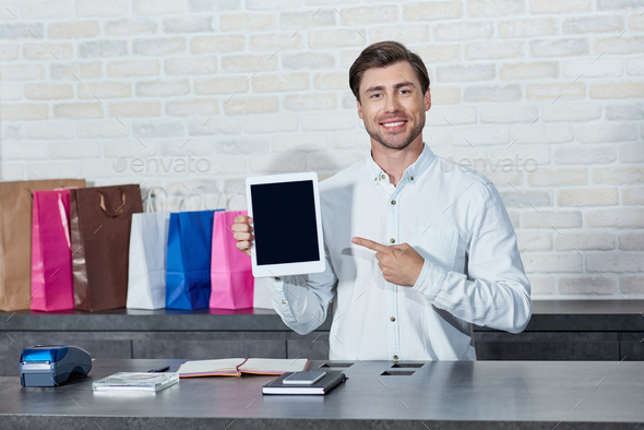 handsome young salesman pointing at digital tablet with blank screen ...
