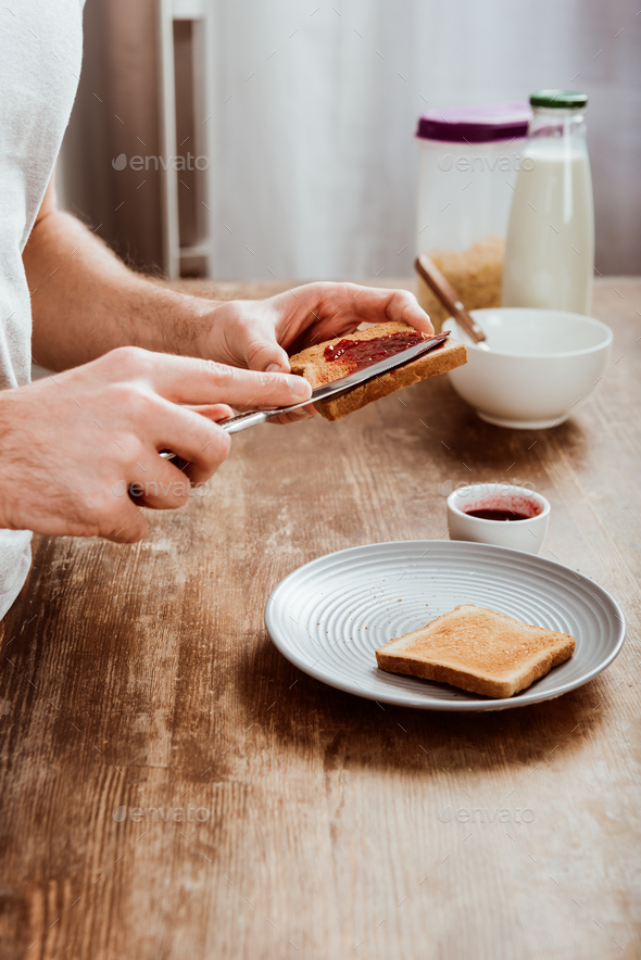 cropped image of man spreading toast by jam in kitchen at home Stock ...