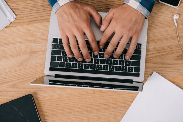 partial view of man using laptop while taking part in webinar at wooden ...