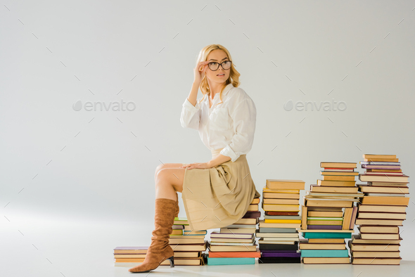 beautiful blonde woman in glasses sitting on pile of retro books Stock ...