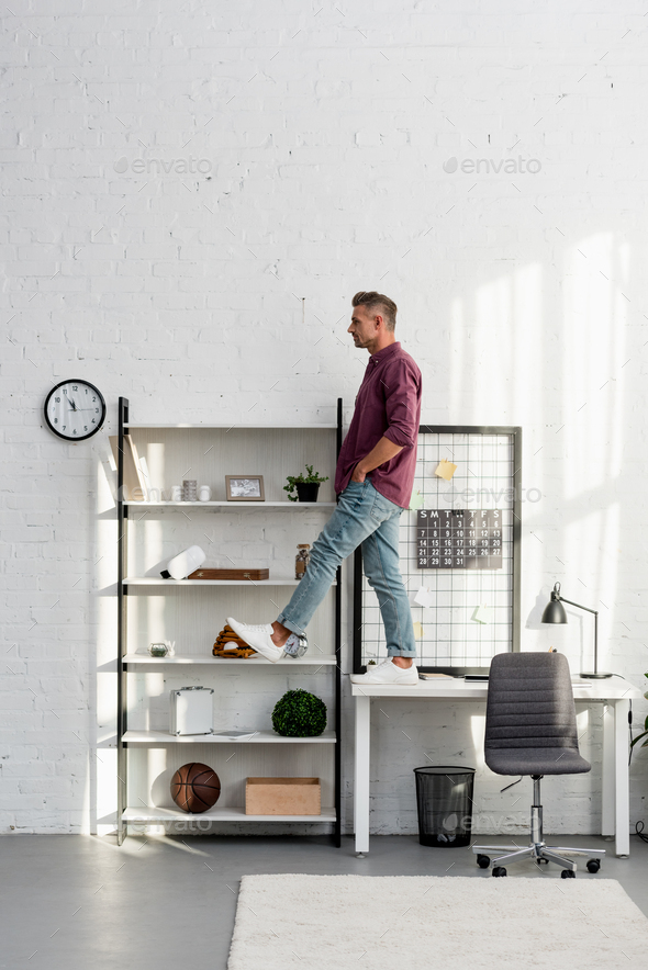 man stepping from desk at home office Stock Photo by LightFieldStudios