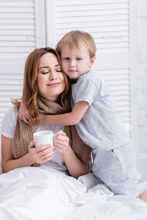 adorable son hugging sick mother in bedroom Stock Photo by ...