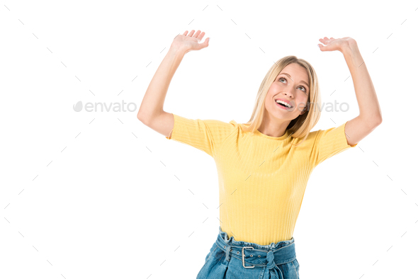 cheerful young woman raising hands and looking up isolated on white ...