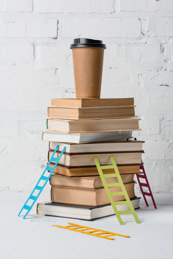 coffee to go on pile of books and small colorful step ladders Stock ...