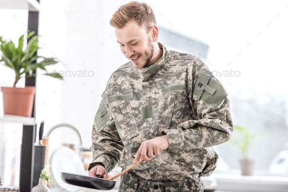 smiling army soldier cooking on pan in kitchen Stock Photo by ...