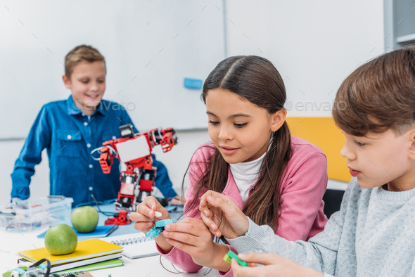 happy classmates making a robot during STEM robotics lesson Stock Photo ...
