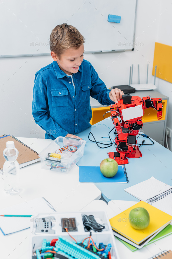 happy schoolboy working on handmade robot model during STEM lesson ...