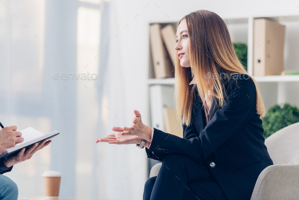 cropped image of businesswoman in suit giving interview to journalist ...