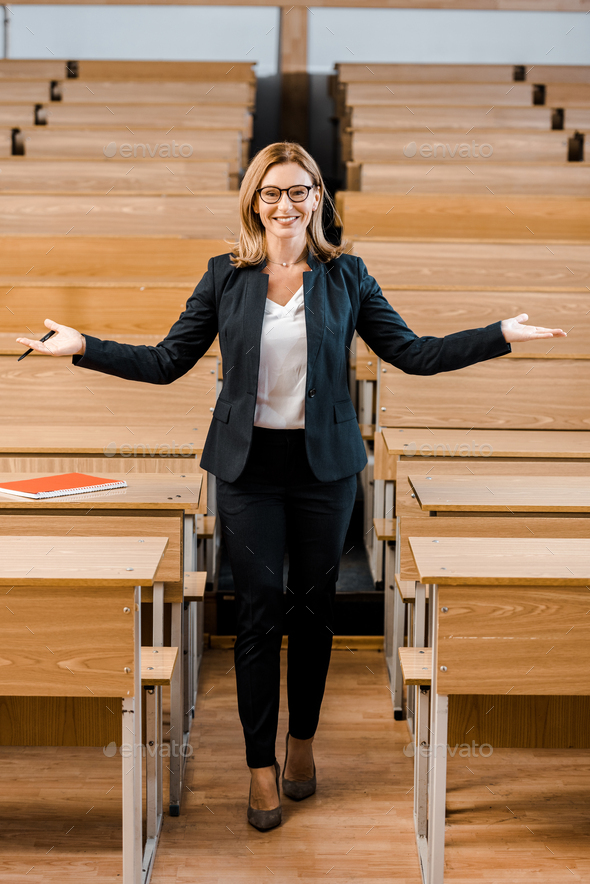 smiling female university professor with outstretched hands looking at ...