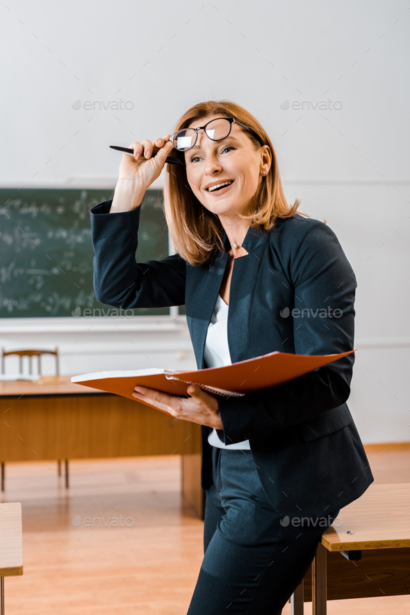 beautiful smiling female teacher in formal wear and glasses holding ...
