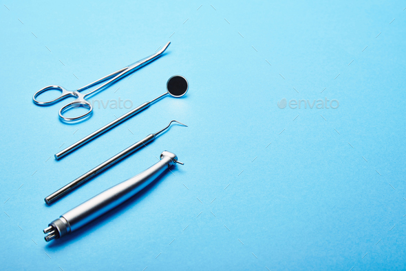 close up view of sterile stainless dental instruments on blue ...