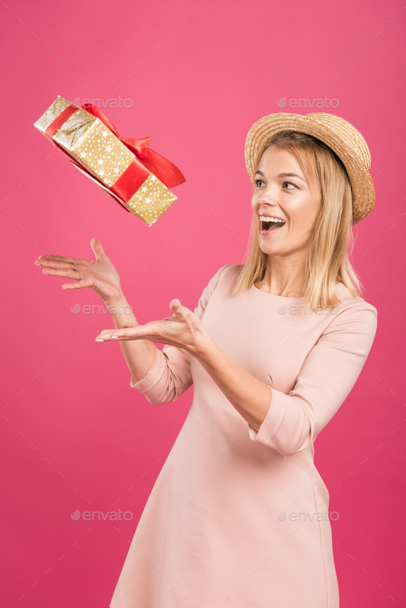 excited blonde woman throwing up gift box isolated on pink Stock Photo ...