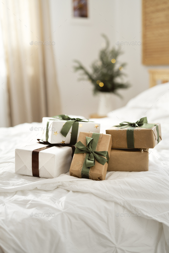 Stack of Christmas present with green ribbon lying on bed Stock Photo ...