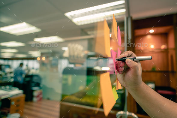 Hand writing paper note, sticky note on glass window with close up shot ...
