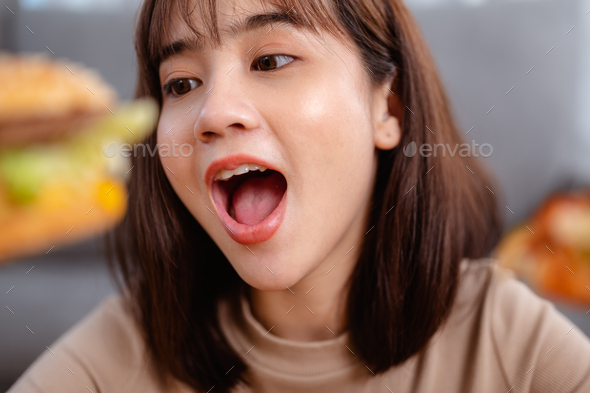 Hungry young woman eating junk food hamburger and pizza for lunch by ...