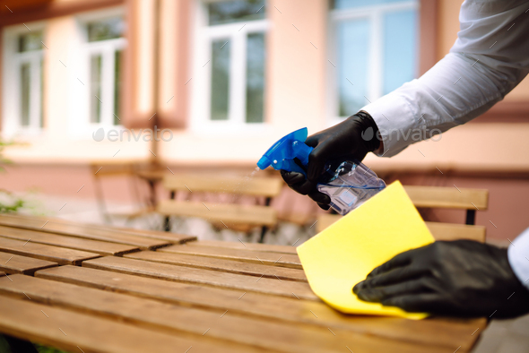 Disinfecting to prevent COVID-19. Waiter cleaning the table with ...