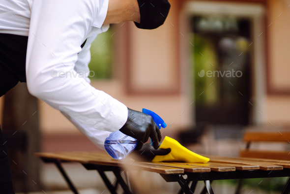 Disinfecting to prevent COVID-19. Waiter cleaning the table with ...