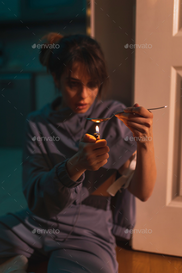 Junkie using lighter and spoon in preparation of intravenous cocaine ...