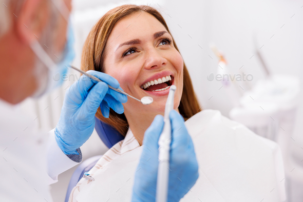 Dentist using dental drill while fixing patient's tooth Stock Photo by ...