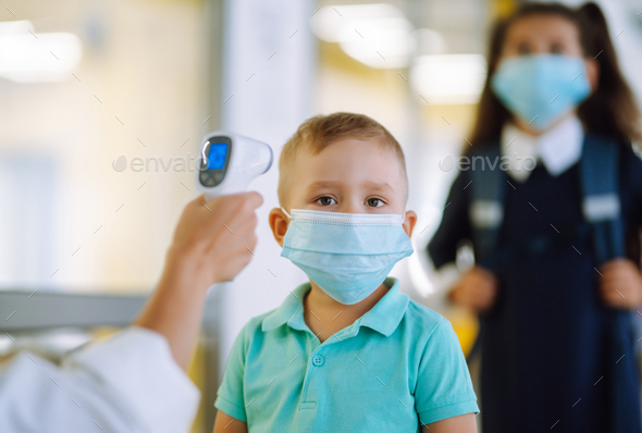Nurse or doctor checks children body temperature using infrared ...