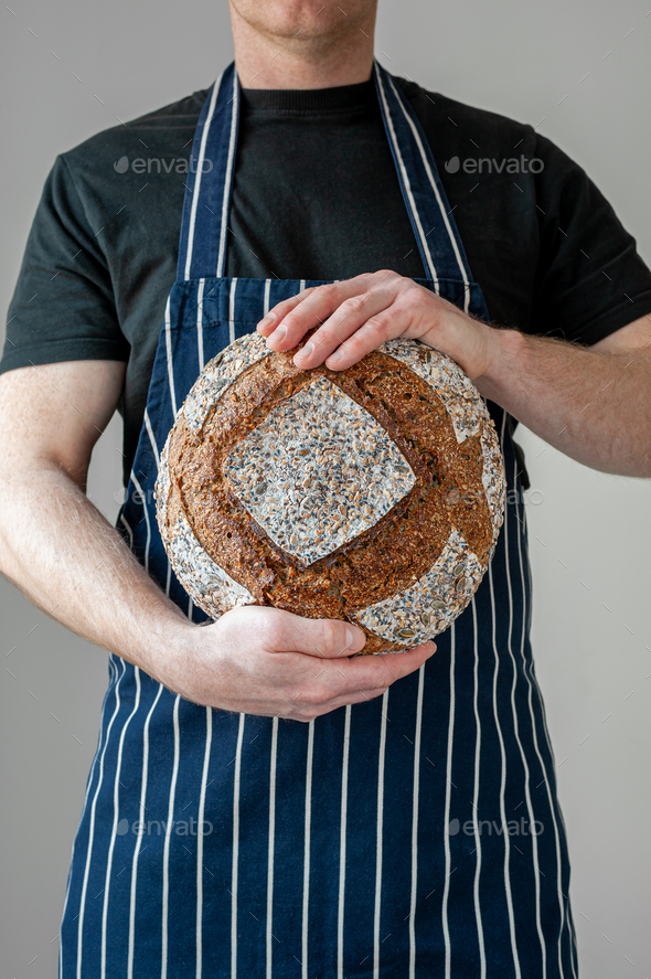 Close-up at bakers hands holding a loaf of bread in front of him. Stock ...