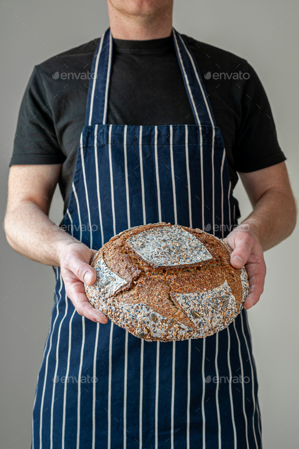 Close-up at bakers hands holding a loaf of bread in front of him. Stock ...