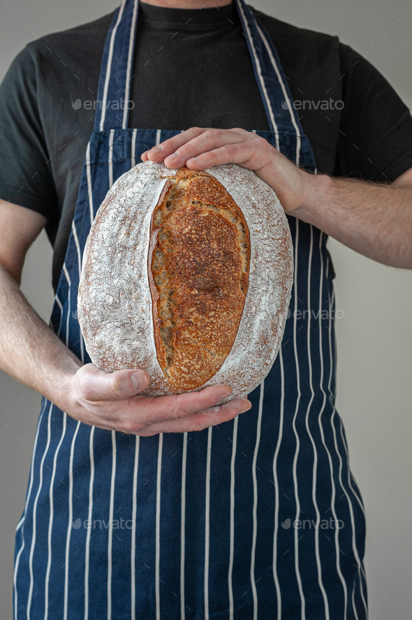 Close-up at bakers hands holding a loaf of bread in front of him. Stock ...
