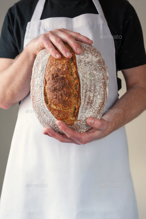 Close-up at bakers hands holding a loaf of bread in front of him. Stock ...