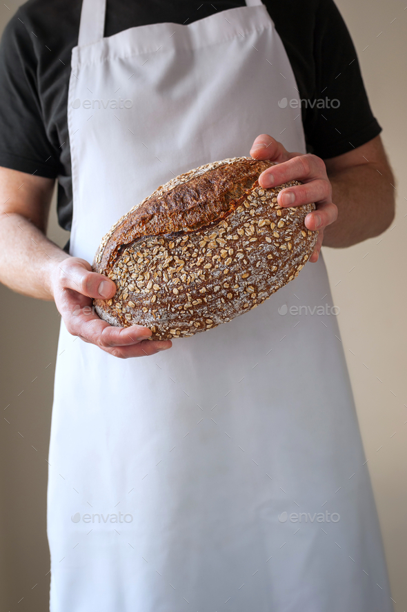 Close-up at bakers hands holding a loaf of bread in front of him. Stock ...