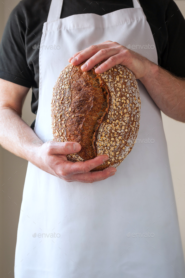 Close-up at bakers hands holding a loaf of bread in front of him. Stock ...