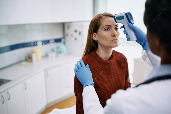 Female patient getting her temperature measured with infrared ...