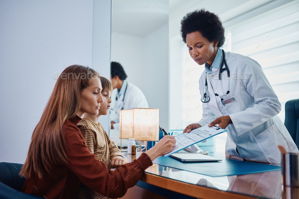 Mother of a boy signing medical document while checking in at doctor's ...