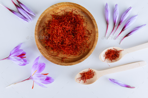 Bunch of saffron stamens, crocus buds, in a wooden plate and spoon on a ...