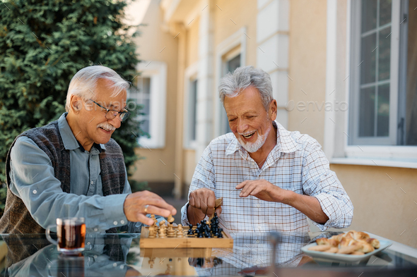 Happy senior men having fun while playing chess on a patio. Stock Photo ...