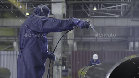 Male holding spray gun and painted steel. Man paints pipe atomizer ...