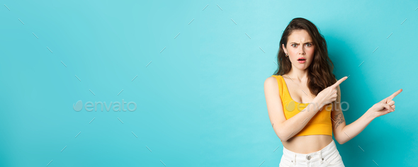 Summer lifestyle concept. Confused young woman pointing at direction ...