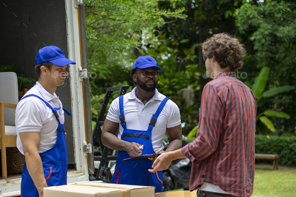 Two delivery men carrying and checking items moving house. Stock Photo ...