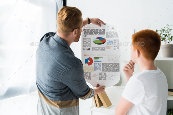 father showing diagram to pensive son at home Stock Photo by ...