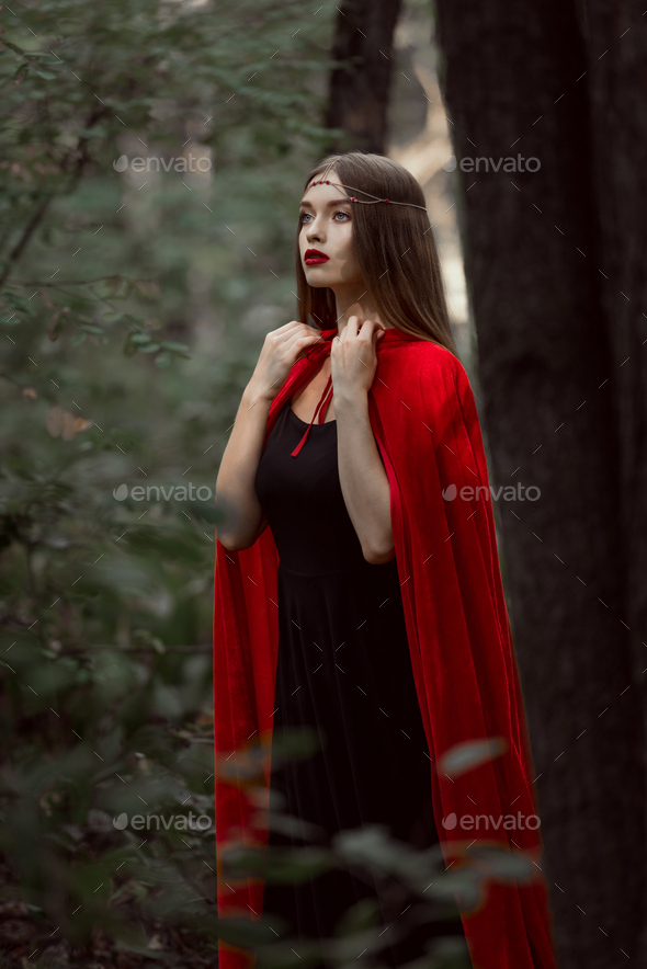 elegant mystic girl in red cloak in woods Stock Photo by LightFieldStudios