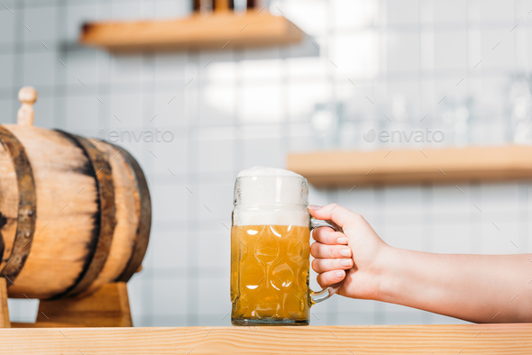 cropped image of female bartender putting mug of light beer with foam ...