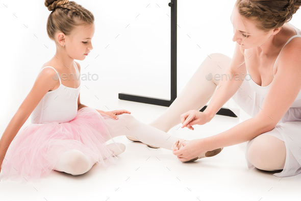 adult female trainer pointing at pointe shoes of little ballerina near ...