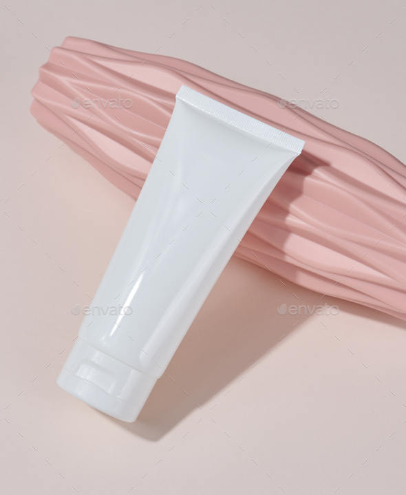 White plastic tube for liquid cosmetics on a beige background ...