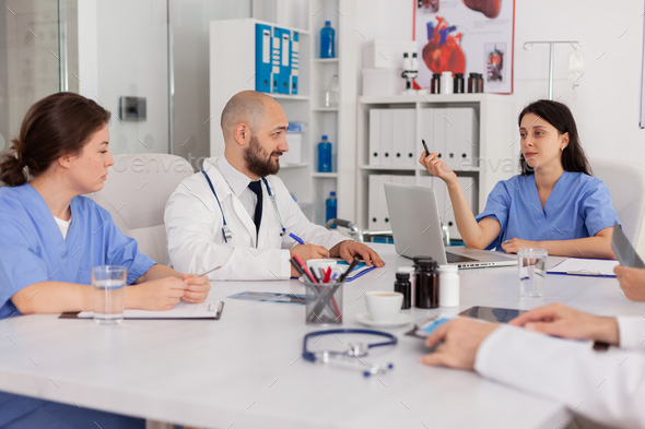 Medical nurse discussing disease examination with research team during ...