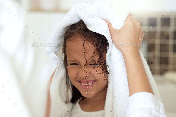 Happy, carefree and smiling little girl drying off after a bath, shower ...