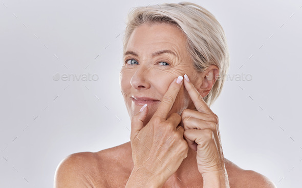 Portrait of one mature caucasian woman popping a zit during a skin care ...