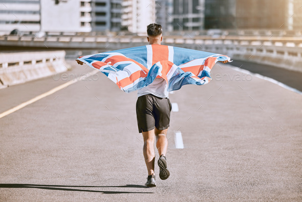 Winner, flag and fitness man running on the city road celebrates ...